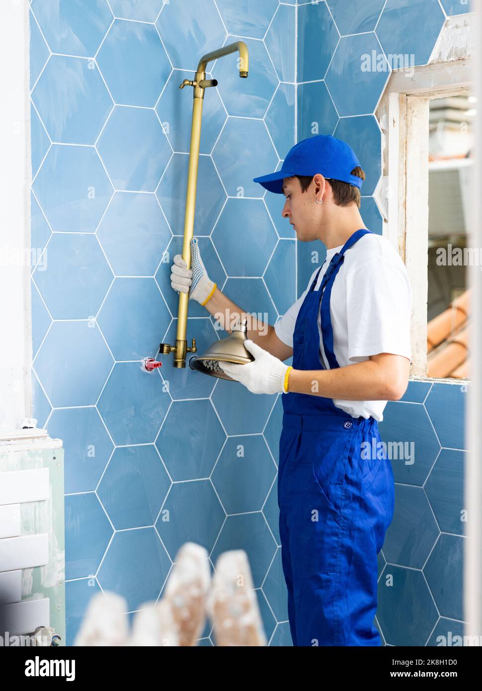 Young builder assembling shower set before fixing to wall Stock Photo ...
