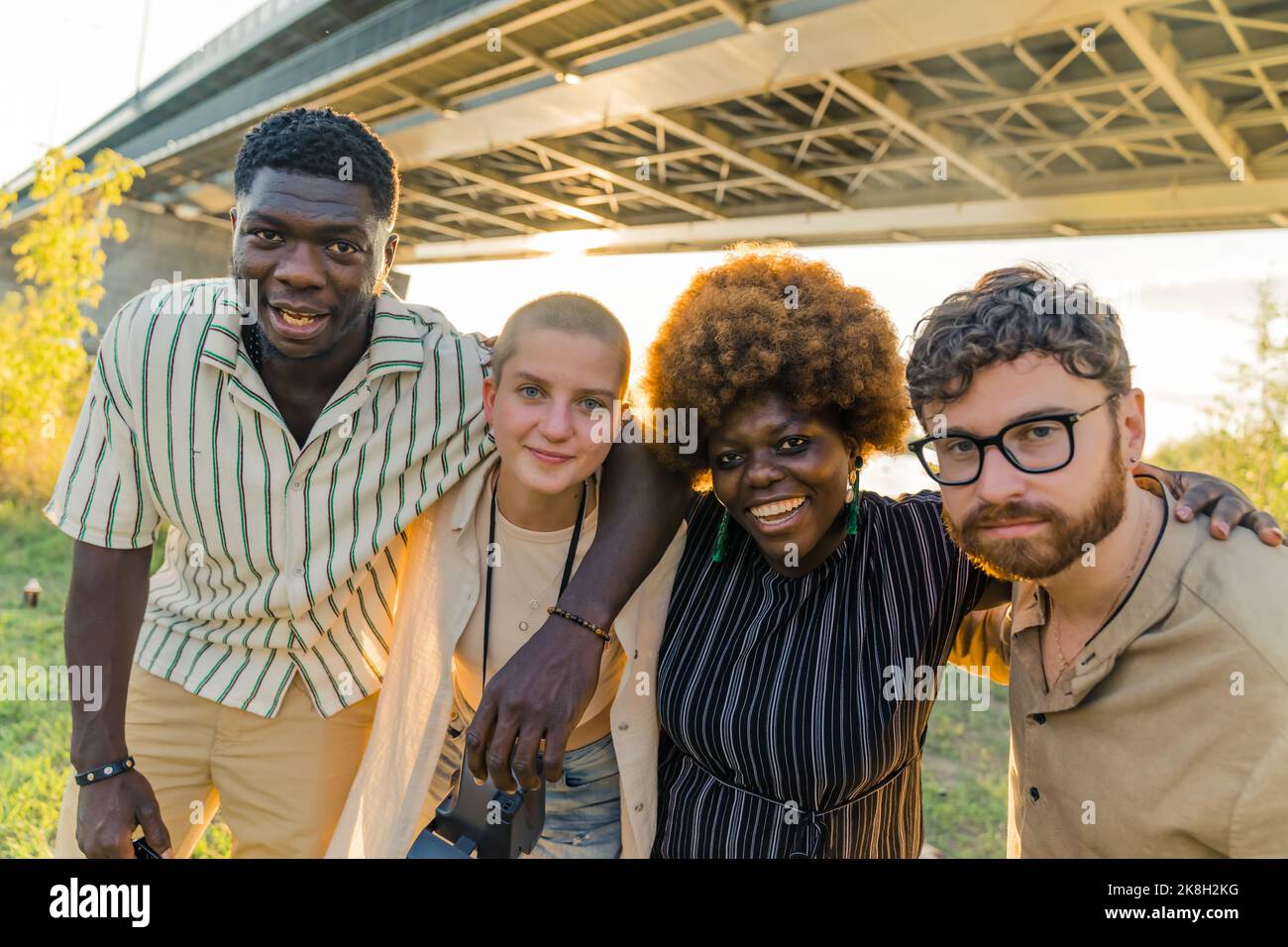 Outdoor portrait of multicultural group of four people looking at camera and smiling ...