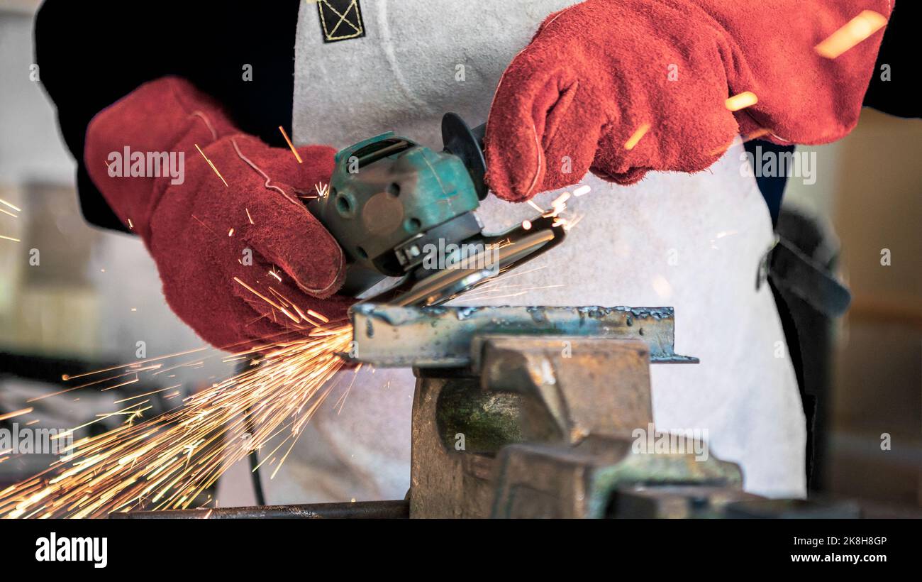 Metal processing with a man using angle grinder to cleaning the steel ...