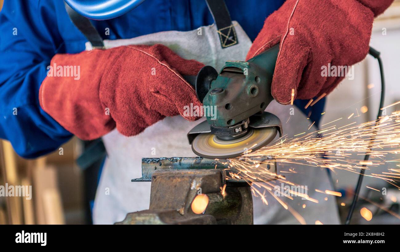Craftsman grinding metal with disk grinder in workshop. Worker cleaning ...