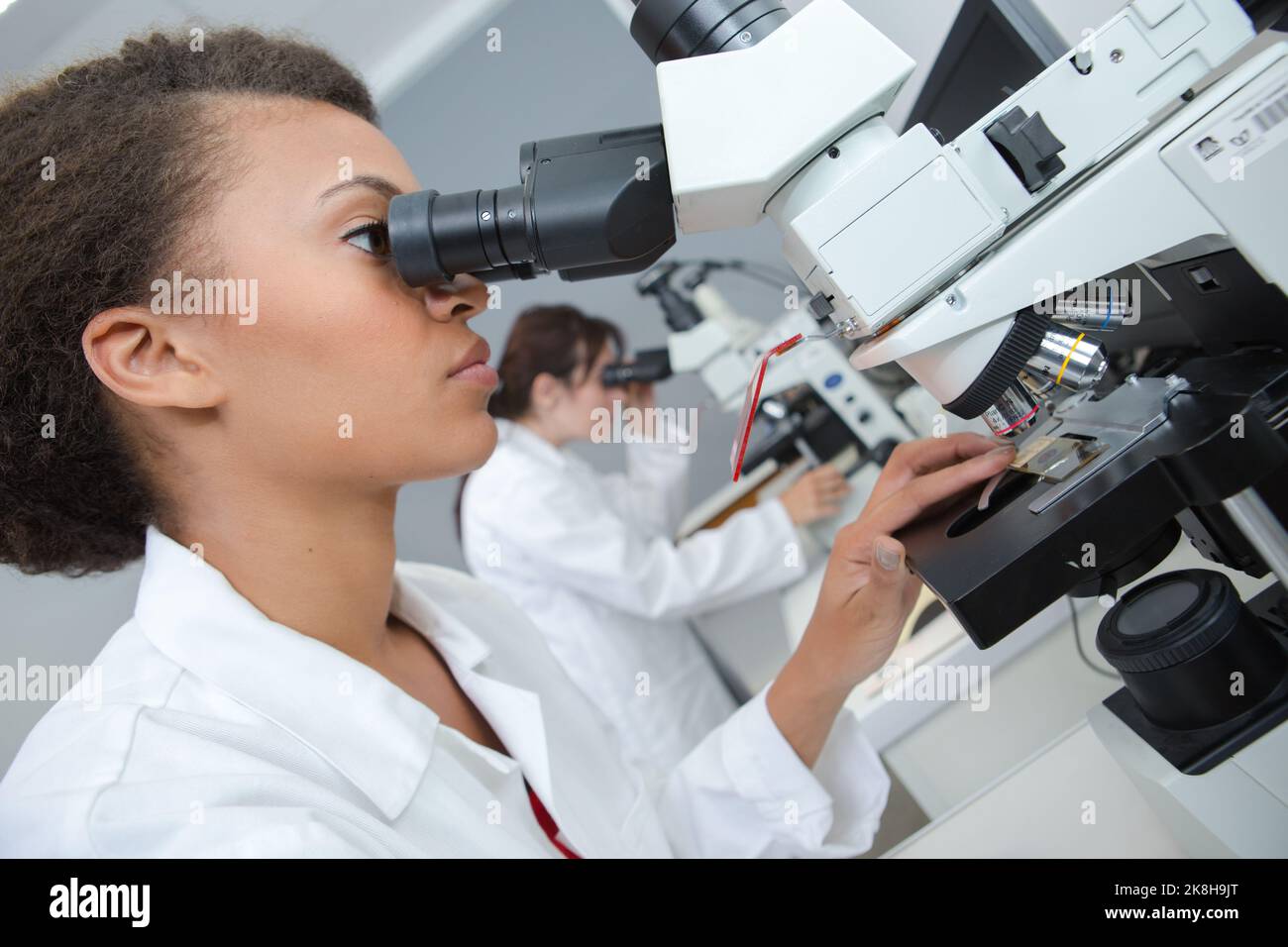 Woman looking into microscope eyepiece hi-res stock photography and ...