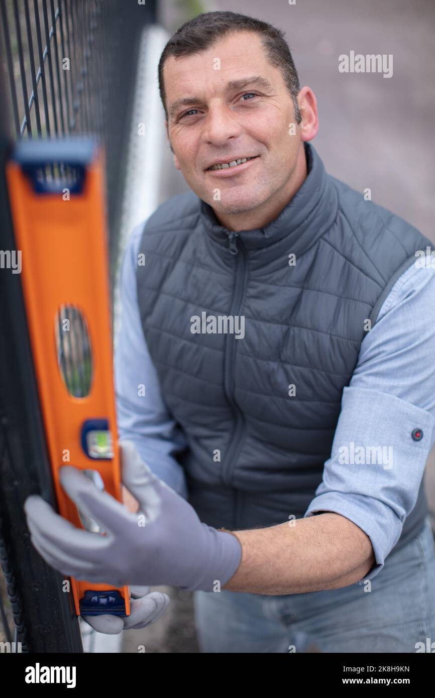 worker checking fence with a spirit level Stock Photo - Alamy