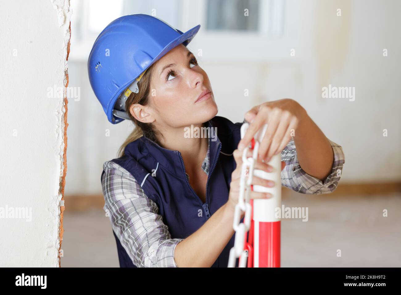 female builder putting up a safety chain Stock Photo - Alamy