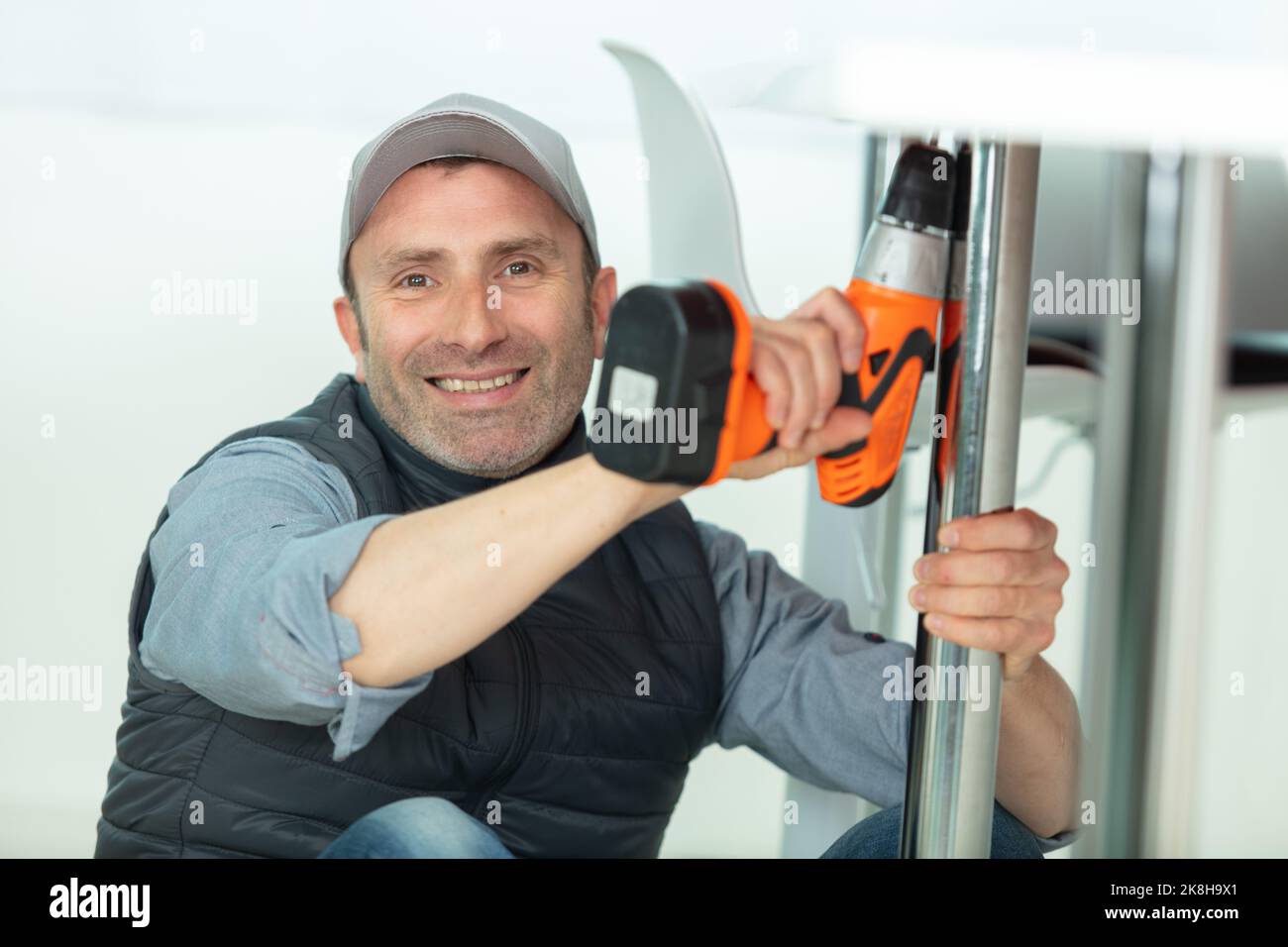 man with an electric screwdriver fixing a table Stock Photo - Alamy