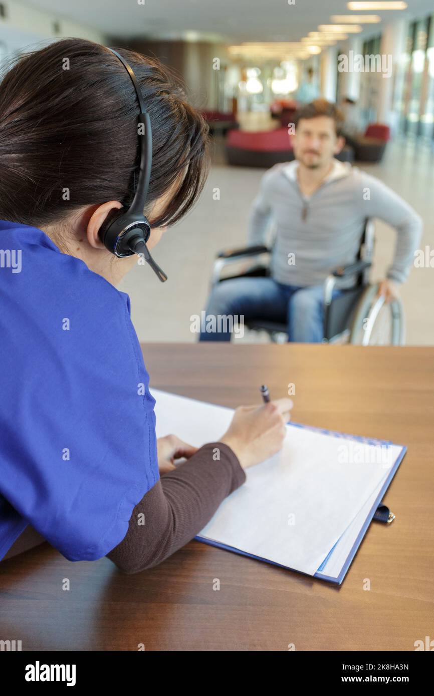 patient in wheelchair while receptionist working Stock Photo - Alamy