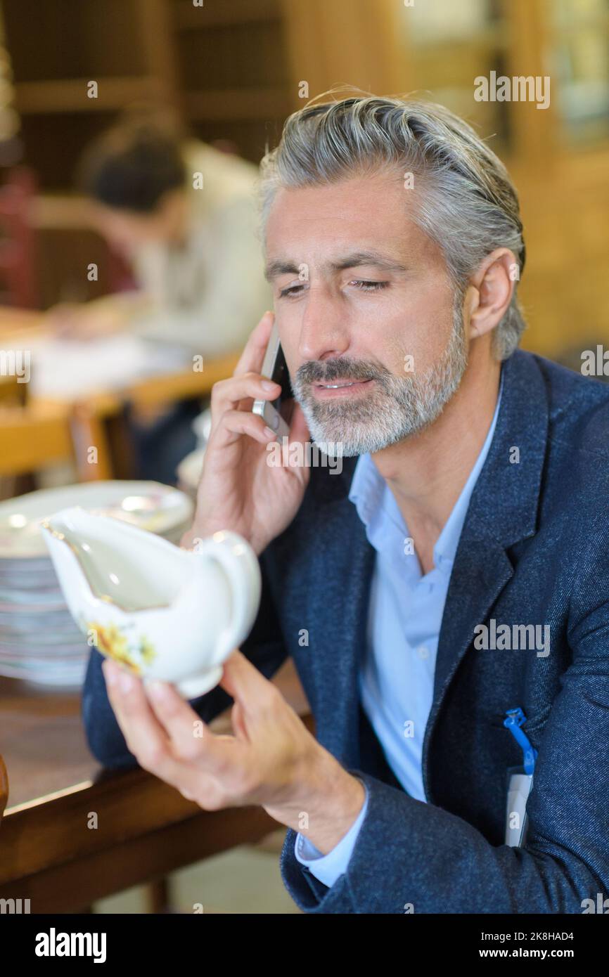 man checking the value of a ceramic pot Stock Photo - Alamy