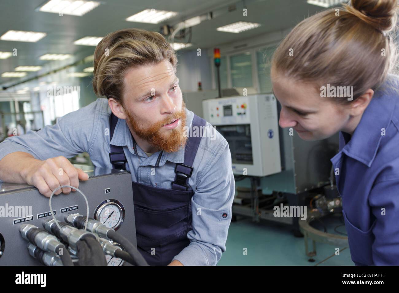 engineer helping female apprentice in factory Stock Photo - Alamy