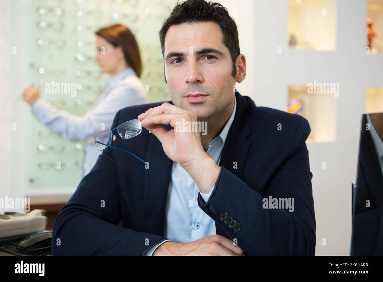 portrait of suited man holding eyeglasses in the opticians Stock Photo ...