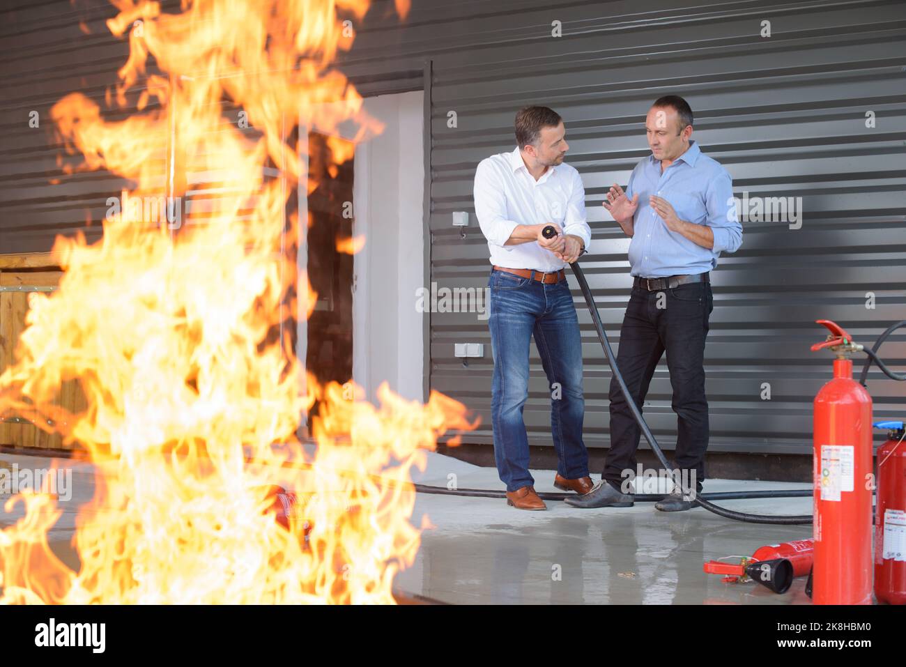 men and fire-extinguisher on flame background Stock Photo - Alamy