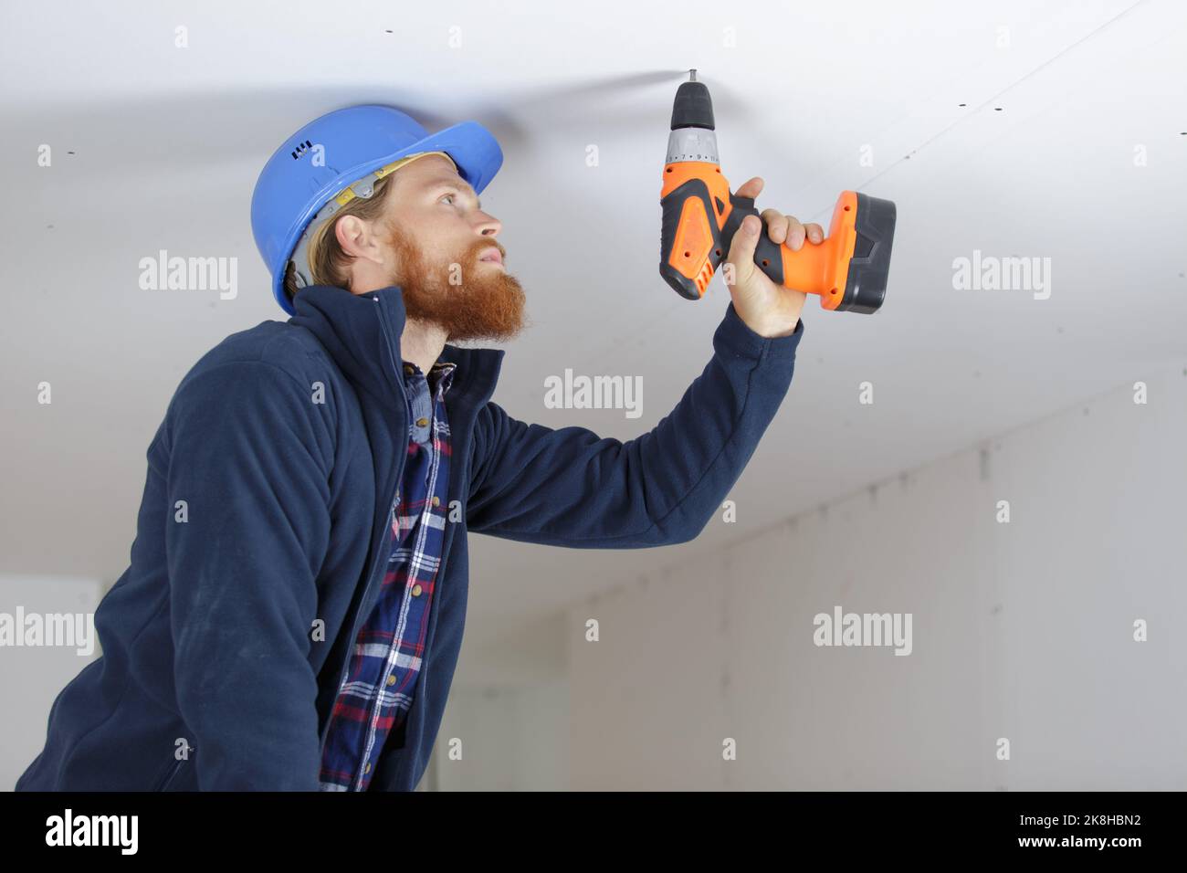 an electrician is drilling a ceiling with a perforator Stock Photo - Alamy