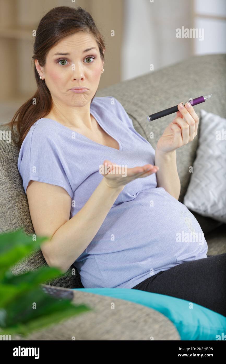 charming girl with baby in belly holding an electronic cigarette Stock ...