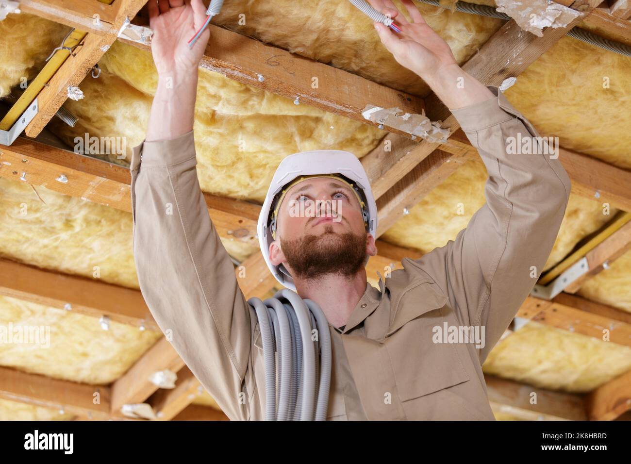 tradesman installing electric cabling around ceiling joists Stock Photo ...