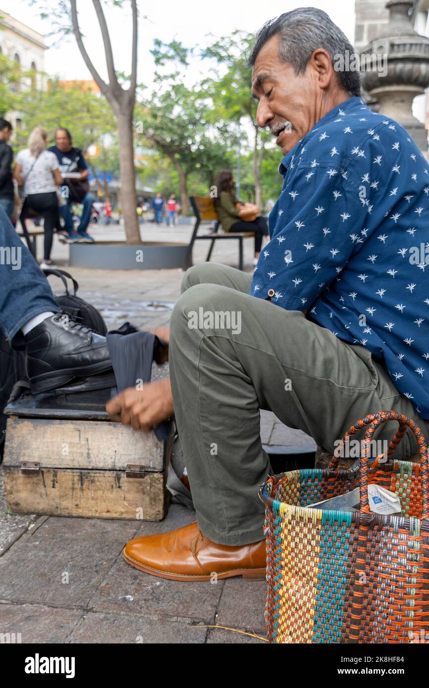 older latino man, dark skinned, cleaning and shining shoes, happy with ...