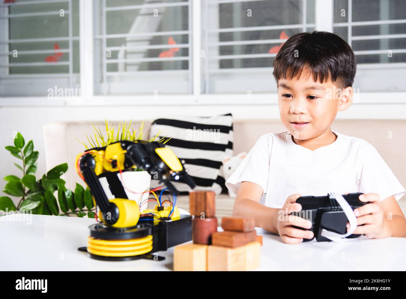 Happy Asian little kid boy using remote control playing robotic machine ...