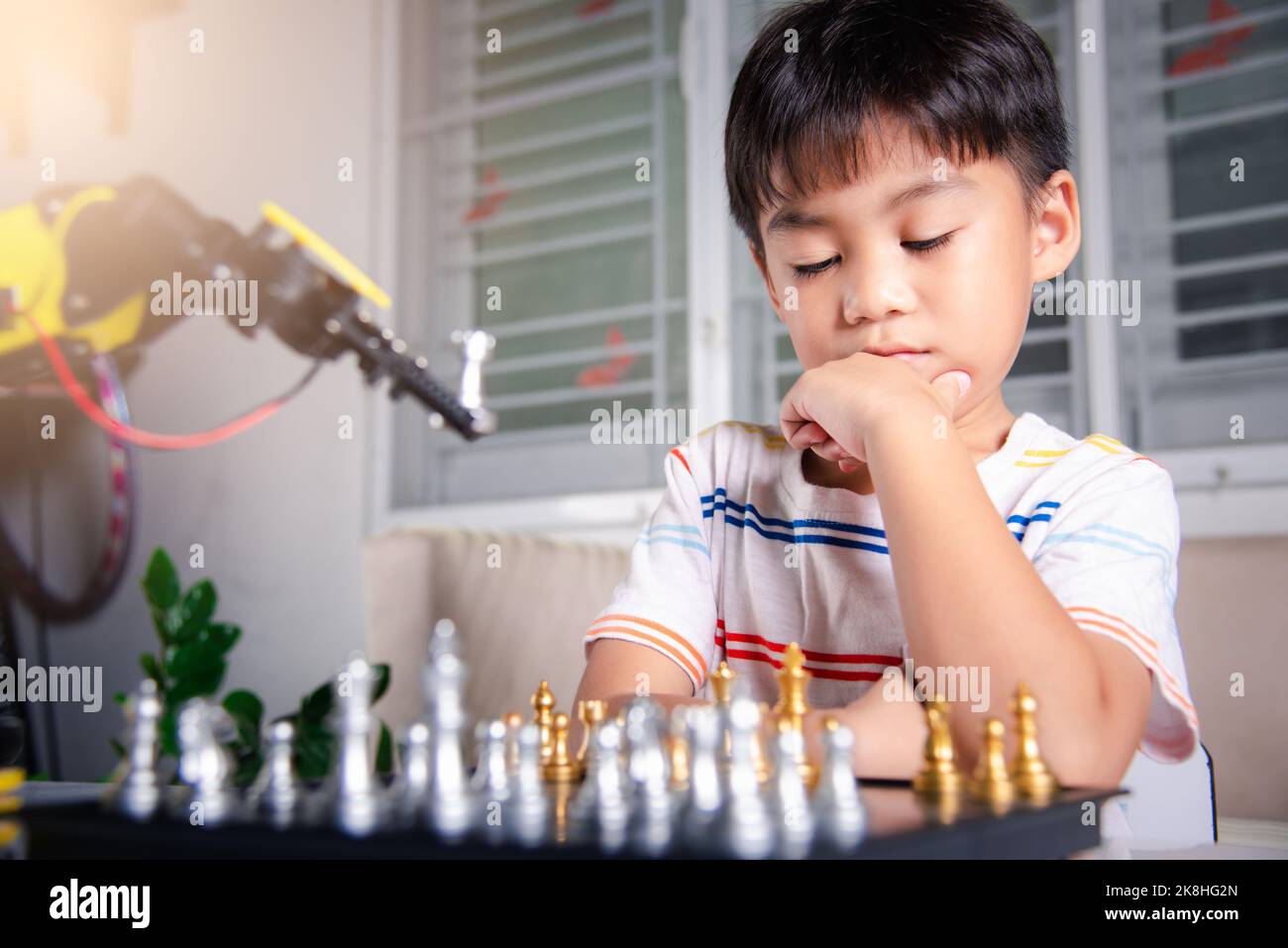 Asian little boy thinking and wait robot arm playing chess, STEM ...