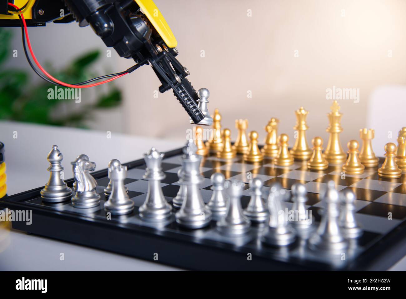 Closeup yellow robot arm playing move chess on chessboard, STEM ...