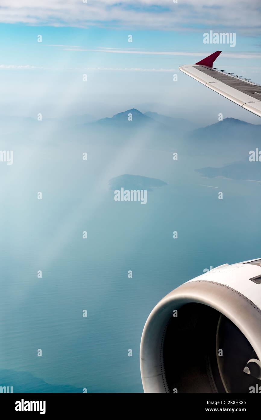 The peaks of Lantau Island with wingtip and engine of a passenger jet ...