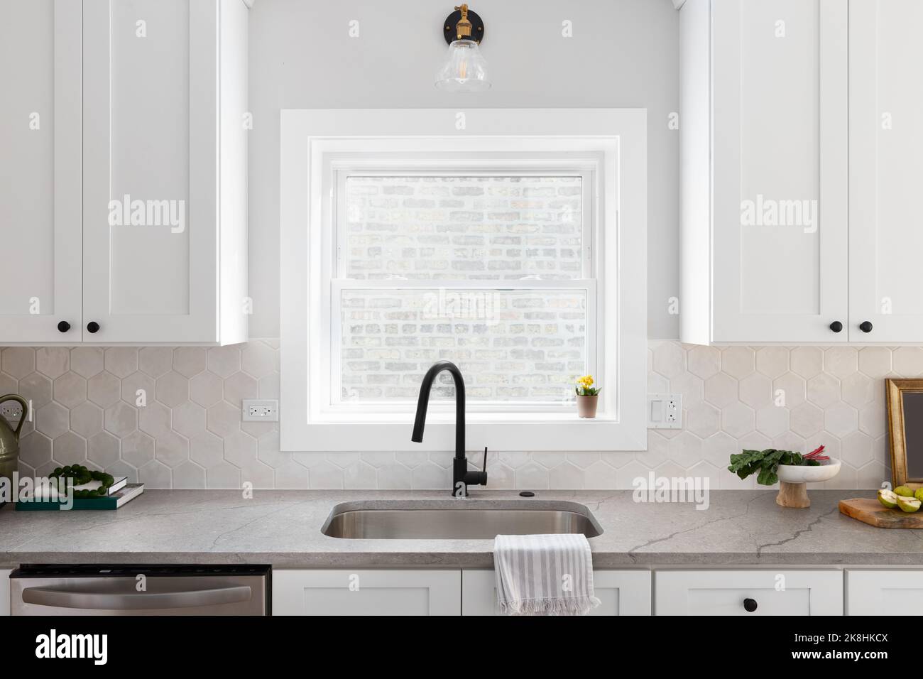 A beautiful kitchen sink detail with white cabinets, marble countertops ...