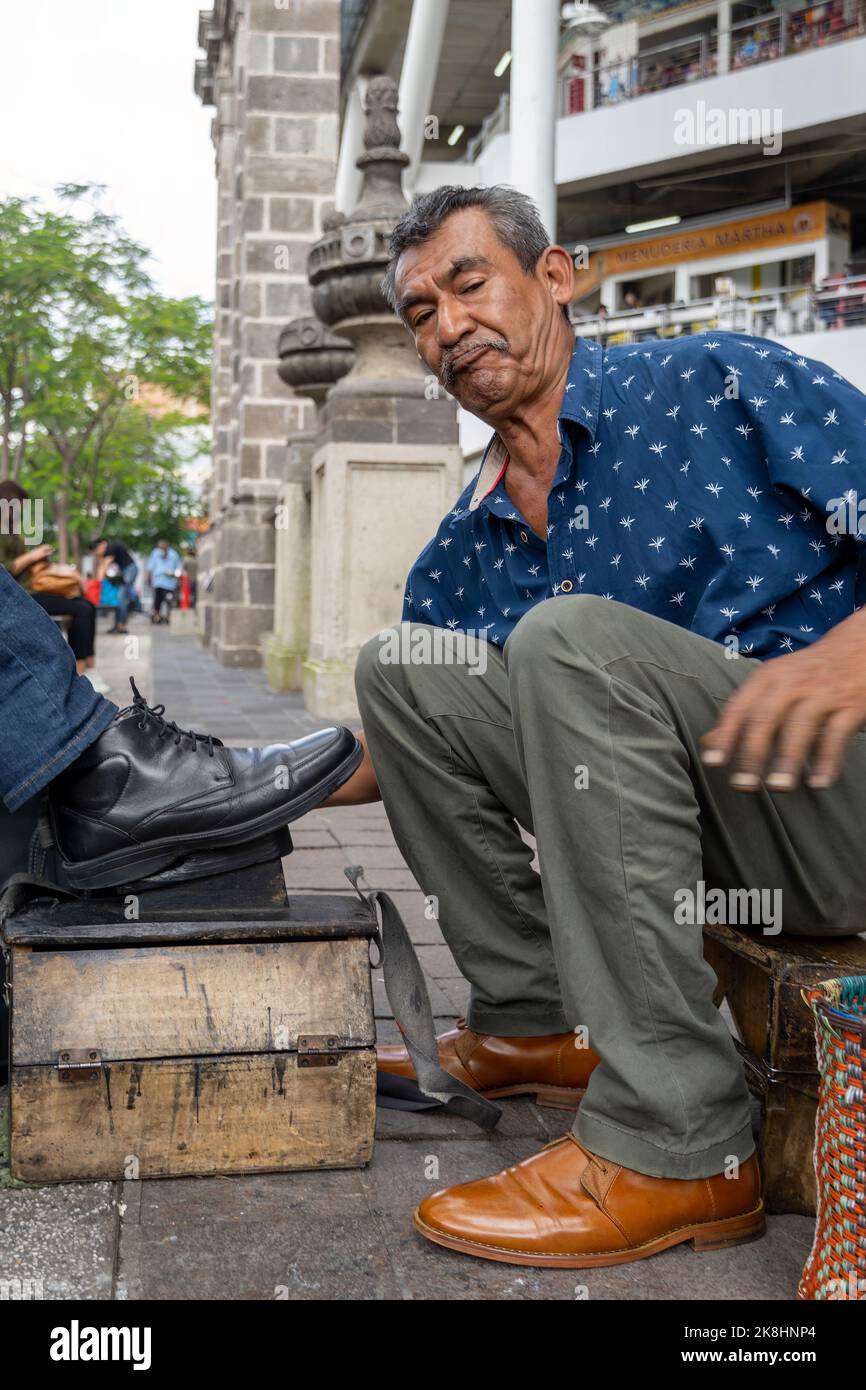 older latino man, dark skinned, cleaning and shining shoes, happy with ...