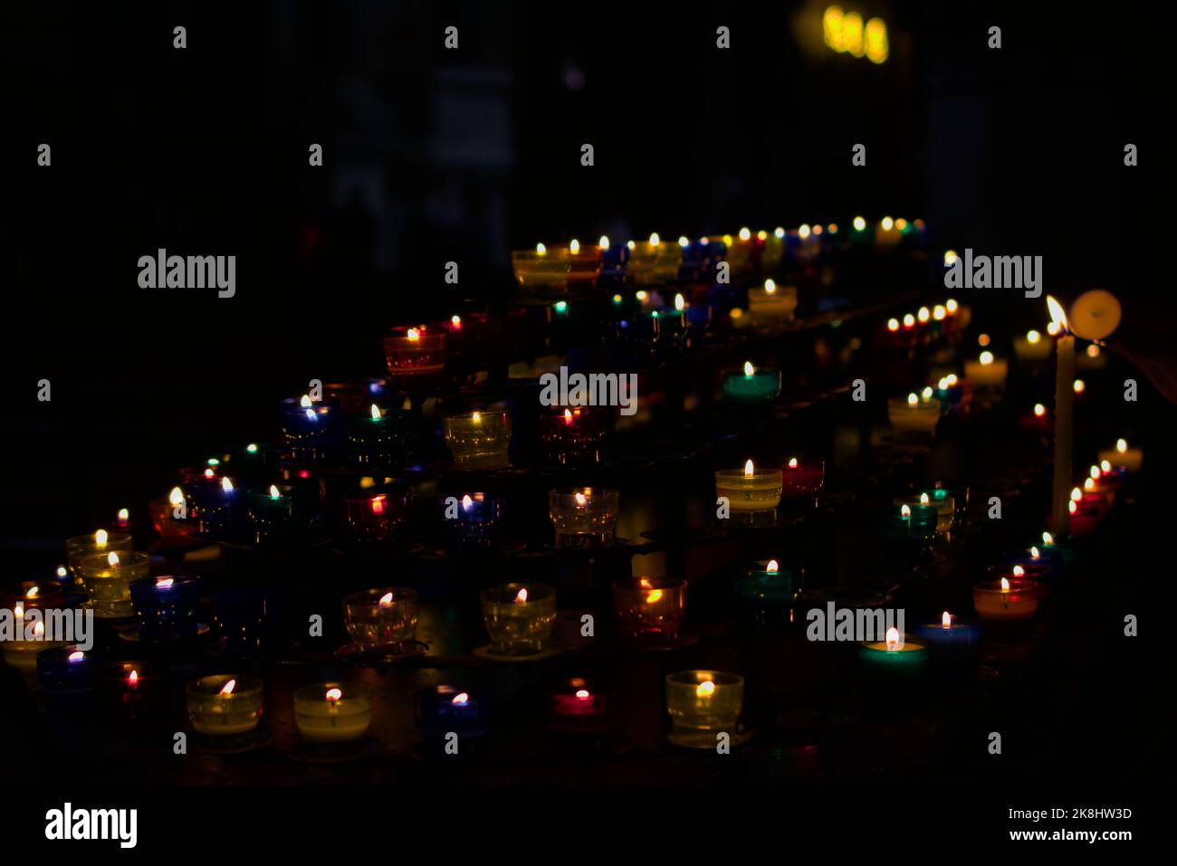 Multi-colored candles lit in a dark church Stock Photo - Alamy