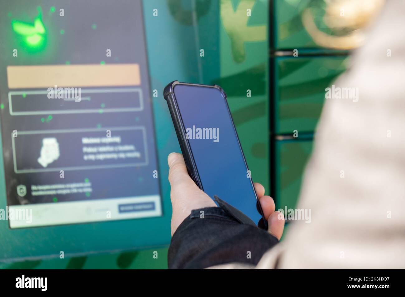 Female hand holding mobile phone next to Parcel locker Collecting ...