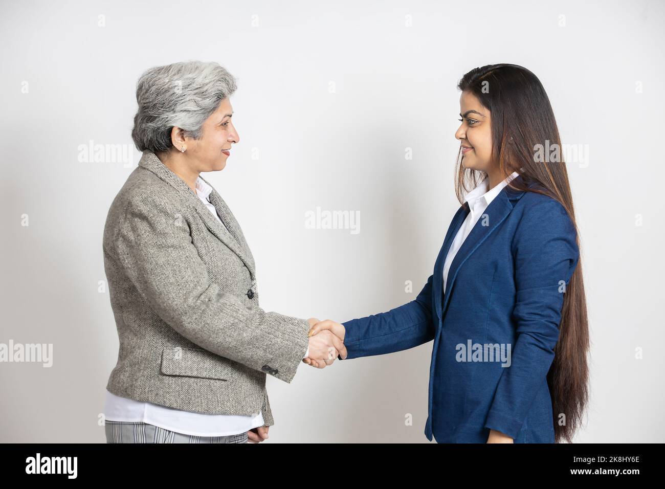 Indian senior corporate female boss hand shake with young business ...