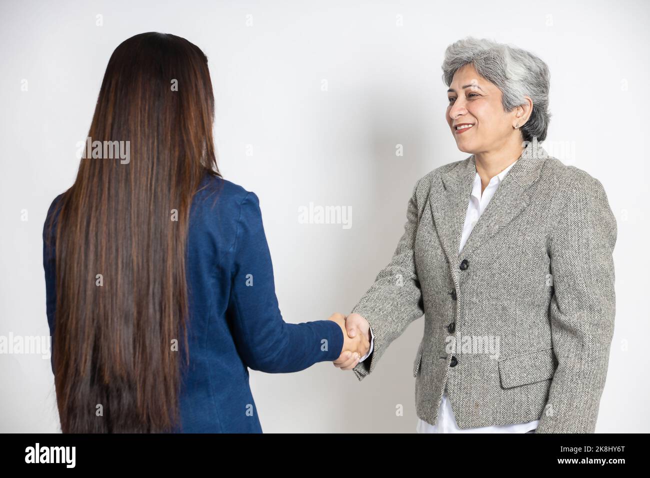 Indian senior corporate female boss hand shake with young business ...
