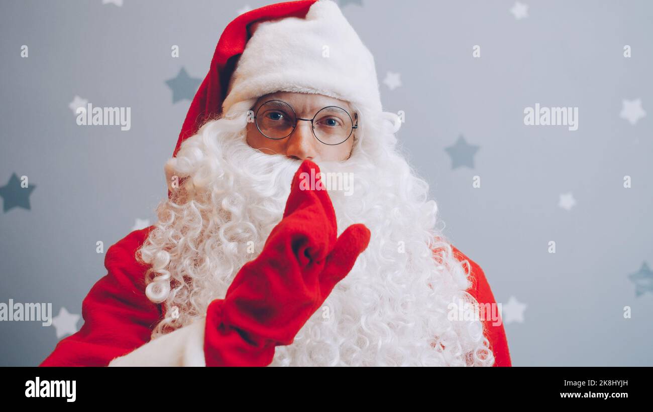 Portrait of Santa in traditional costume making shush hand gesture and ...