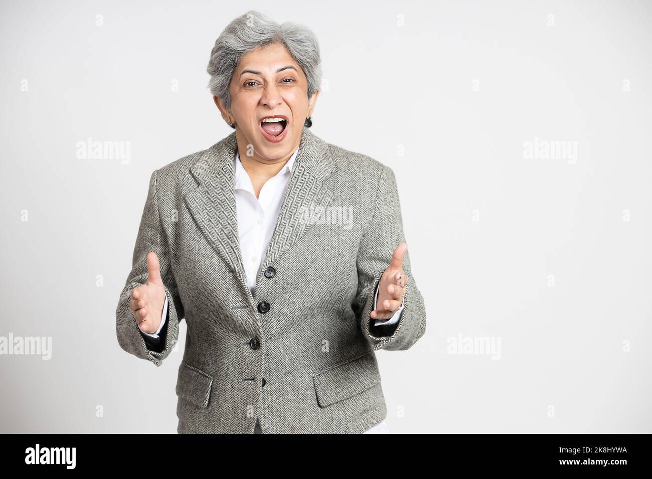 Angry indian senior businesswoman boss in suit standing against white ...