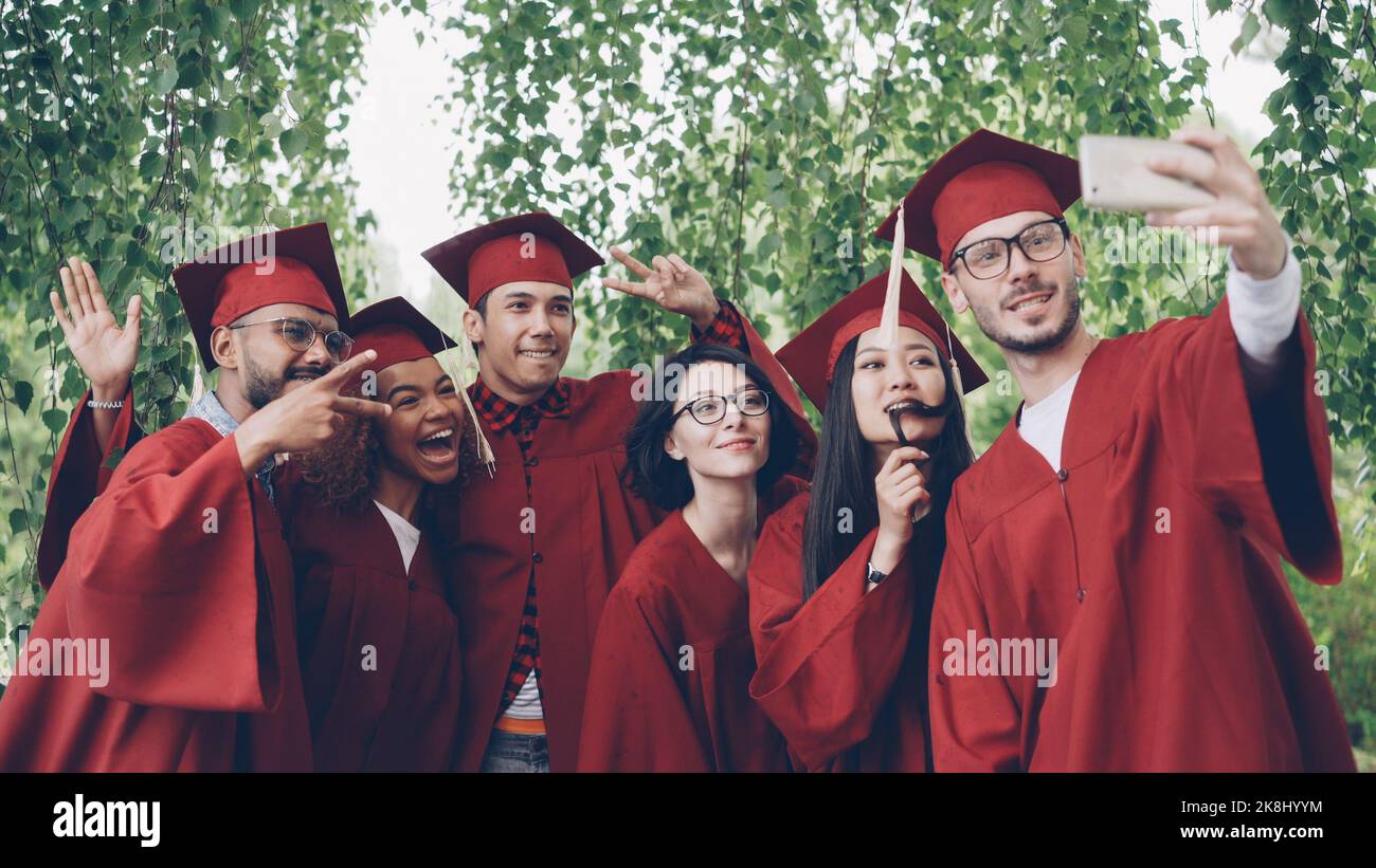 Cheerful friends graduating students are taking selfie with smartphone ...