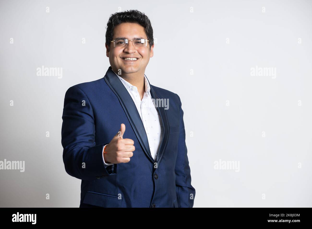 Portrait of a confident young indian business man in a suit do thumbs ...