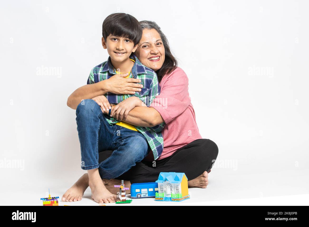 Portrait of happy indian grandmother and grandson hug sit on floor ...