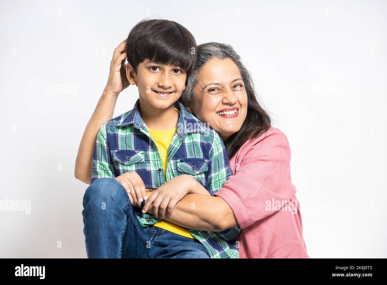 Portrait of happy indian grandmother and grandson hug sit on floor ...