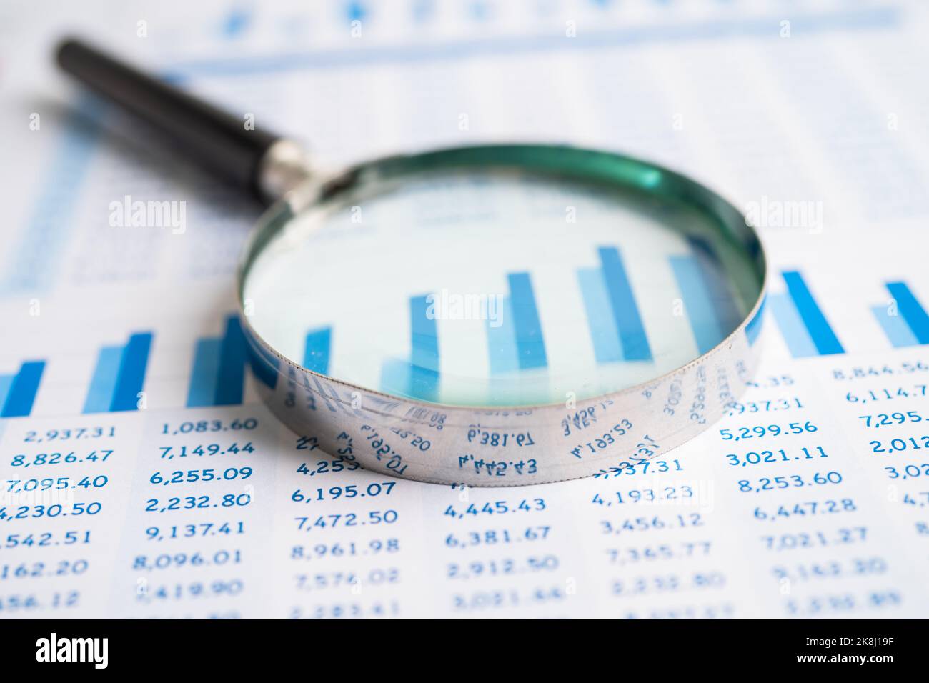 Magnifying glass on chart graph spreadsheet paper. Financial ...