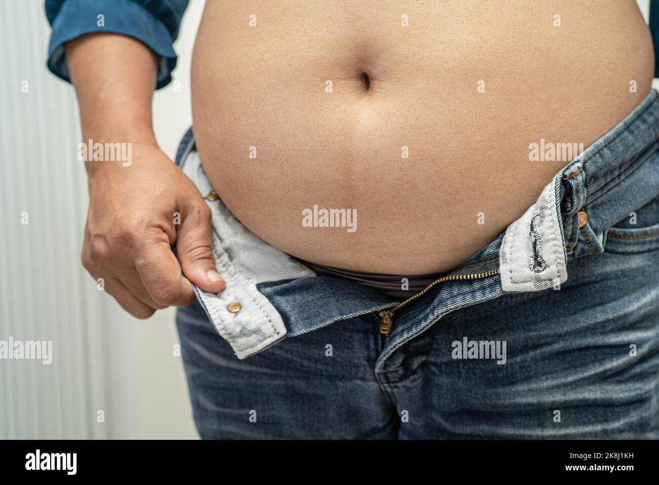 Overweight Asian woman show fat belly at office Stock Photo - Alamy