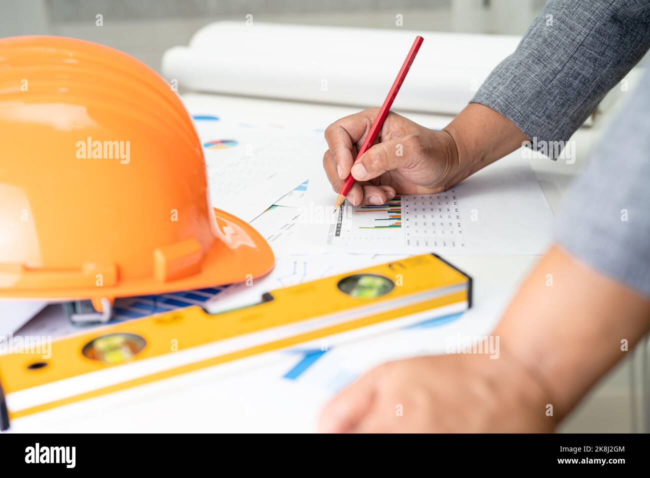 Asian engineer with architectural house plan project blueprint, graph and yellow helmet and ...