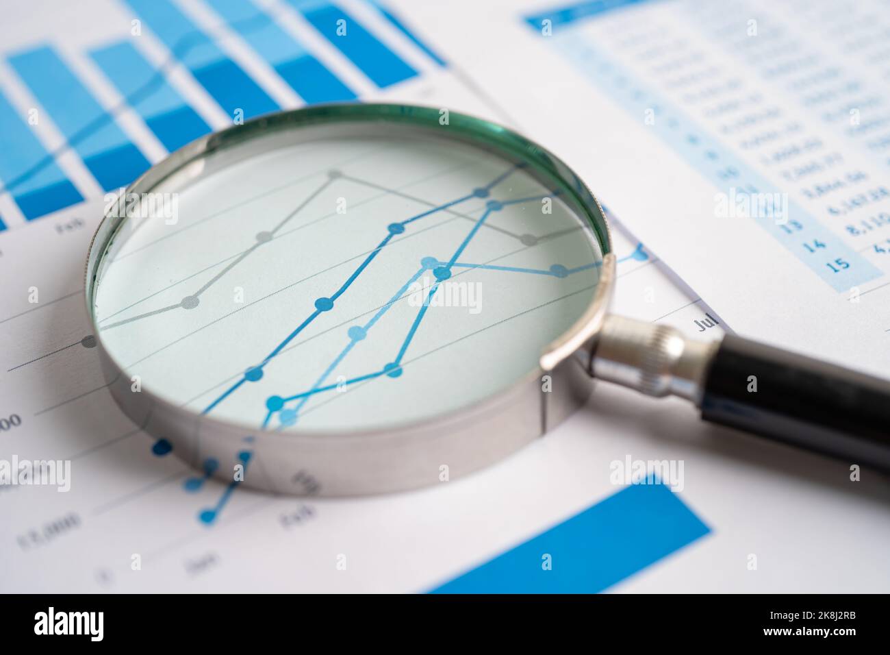 Magnifying glass on chart graph spreadsheet paper. Financial ...