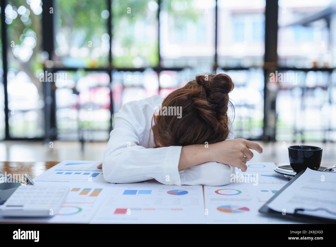 Portrait of a woman employee showing fatigue working on paperwork Stock ...