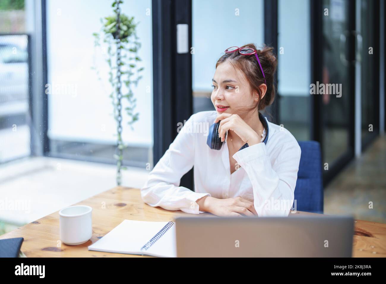 woman showing a smiling face and using a computer and notebook to work ...