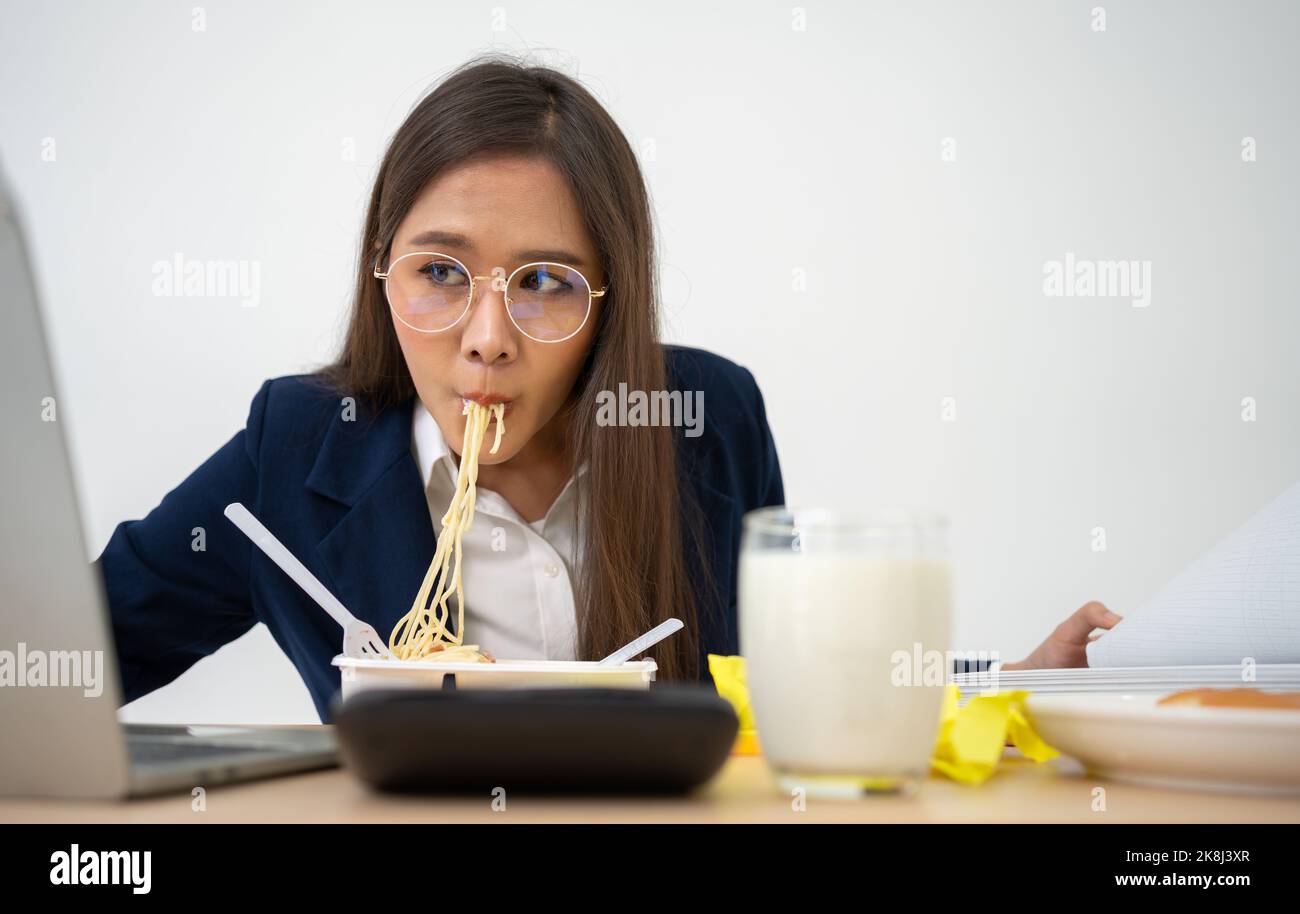 Busy and tired businesswoman eating spaghetti for lunch at the Desk ...