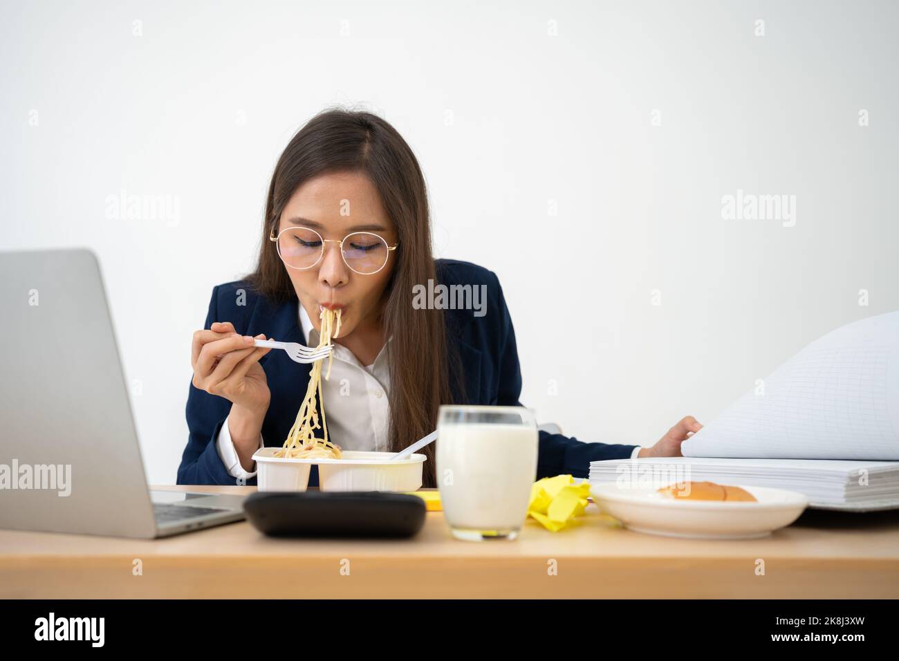 Busy and tired businesswoman eating spaghetti for lunch at the Desk ...