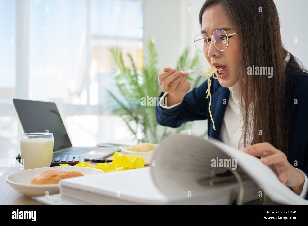 Busy and tired businesswoman eating spaghetti for lunch at the Desk ...