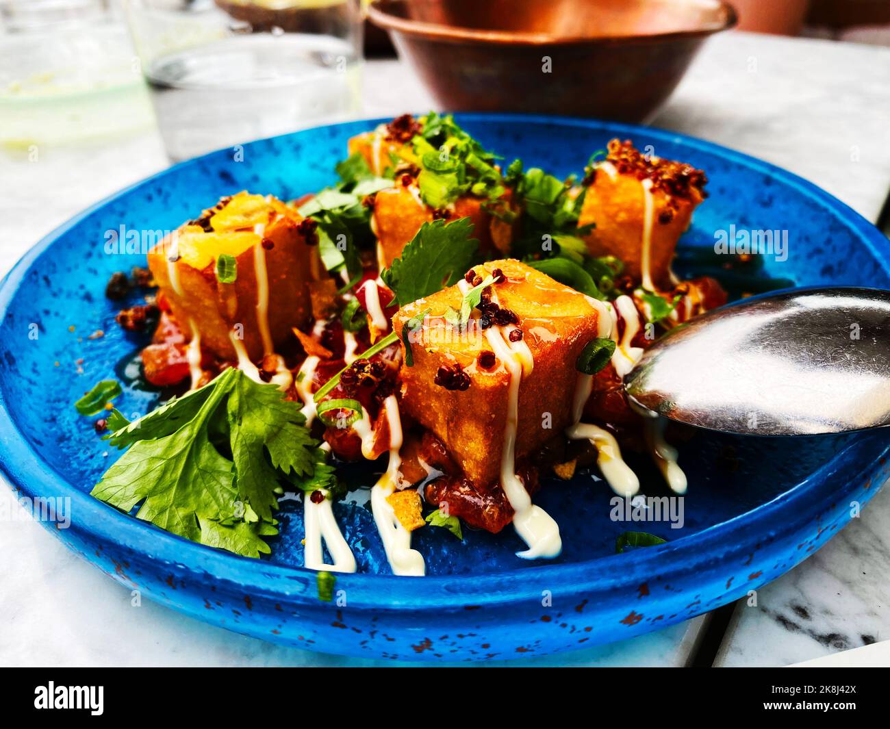A tofu salad. Tofu salad with greens on a blue plate at a fancy rooftop ...