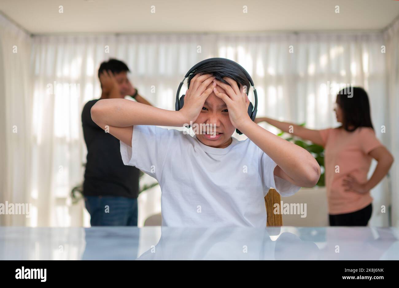 Asian boy kid wearing headphones and play loud music. so as not to hear ...