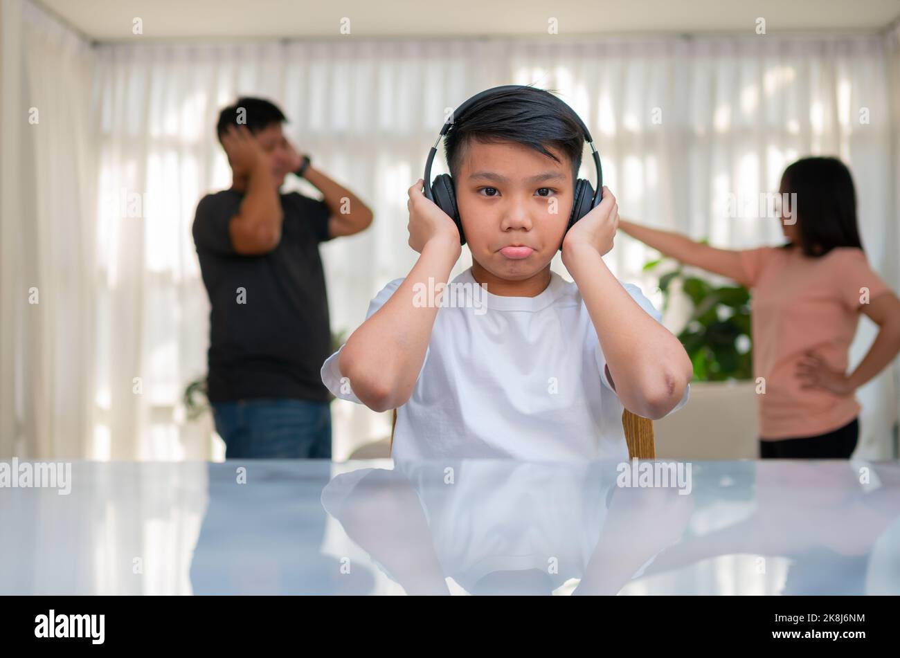 Asian boy kid wearing headphones and play loud music. so as not to hear ...