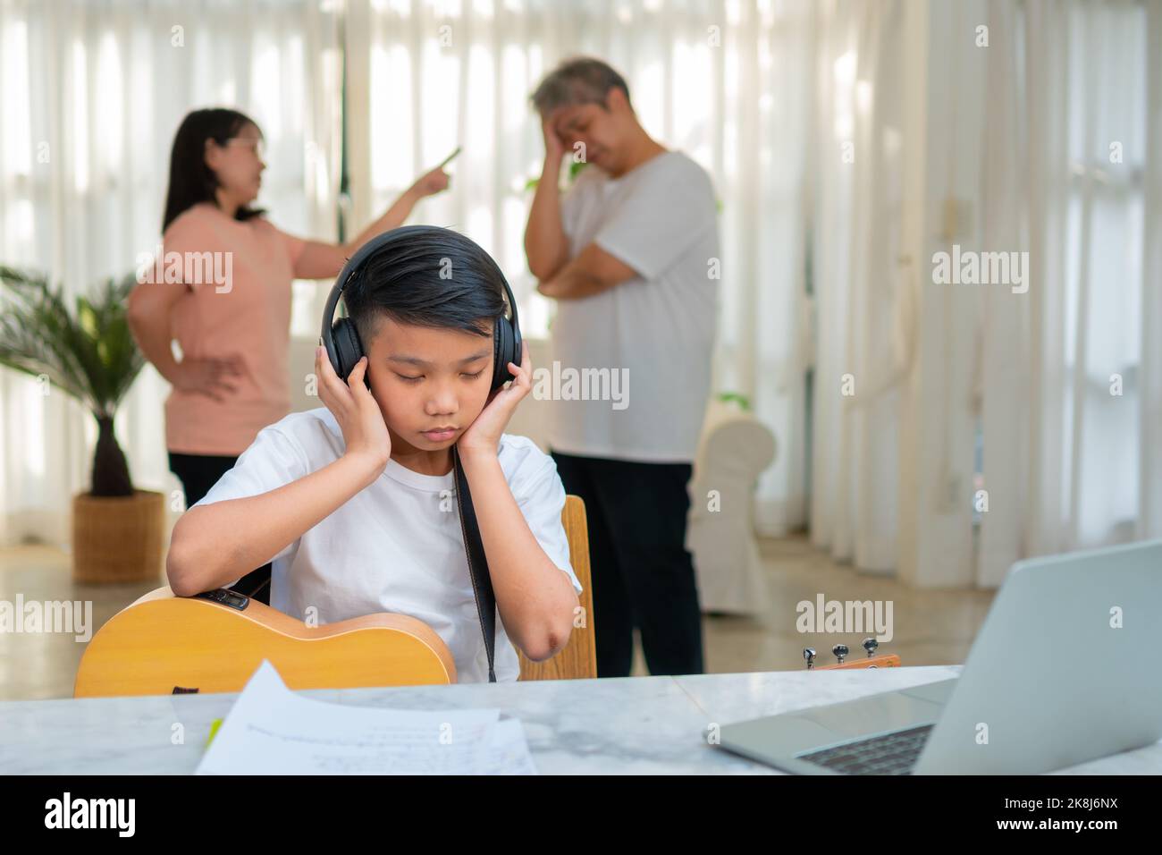 Asian boy kid wearing headphones and play loud music. so as not to hear ...