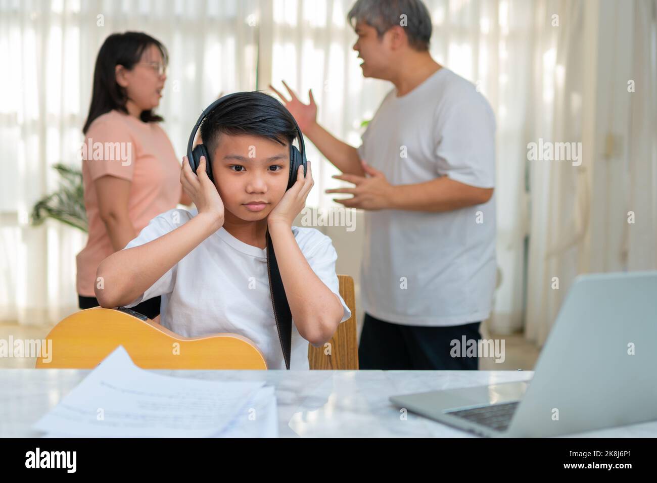 Asian boy kid wearing headphones and play loud music. so as not to hear ...