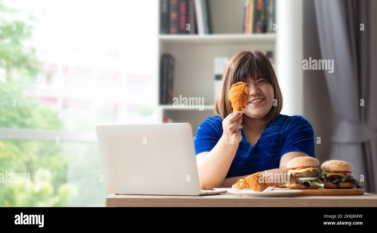 Hungry overweight woman holding Fried Chicken, hamburger on a wooden ...