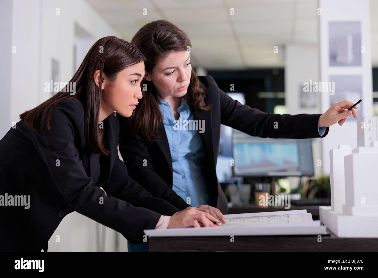 Engineers coworking, discussing building 3d model, working with architecture draft ...