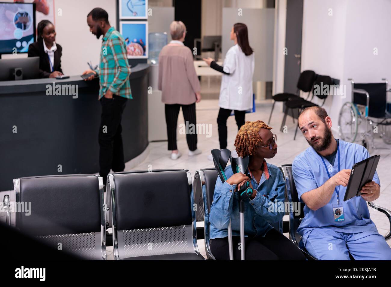 Medical clinic patient reception area filled with multiple nationalities people. African ...